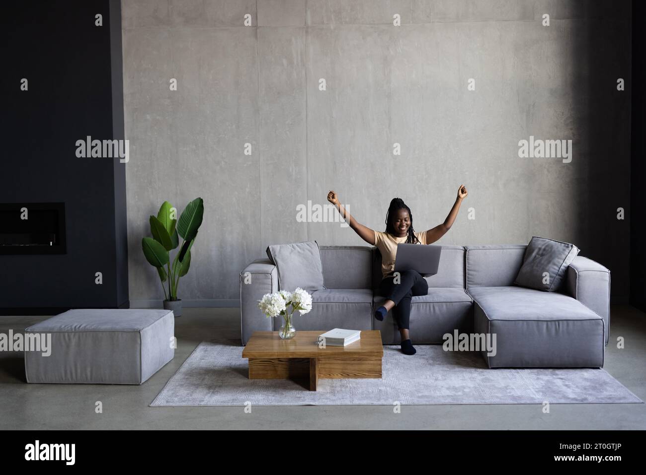 Excited cheerful young Black woman using laptop computer on sofa at ...