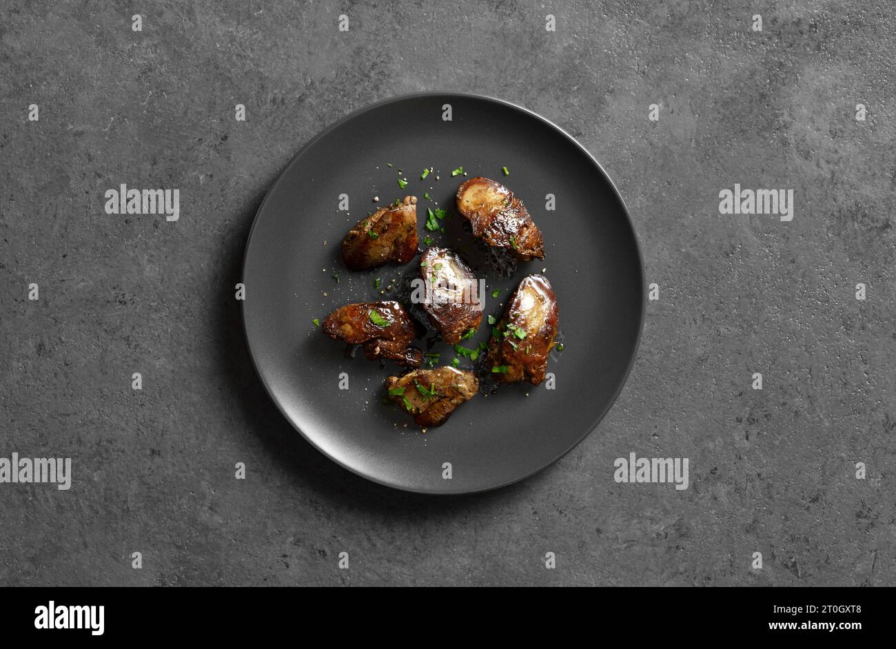 Roasted chicken liver on plate over dark stone background. Top view ...