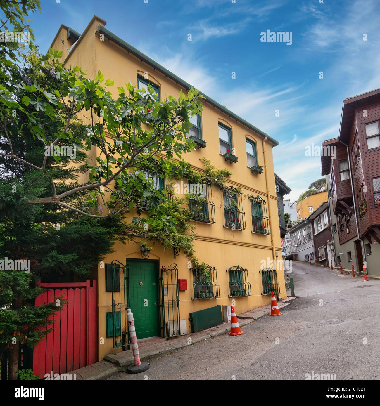 Facade of residential building with walls painted in orange and green, with wrought iron window ...
