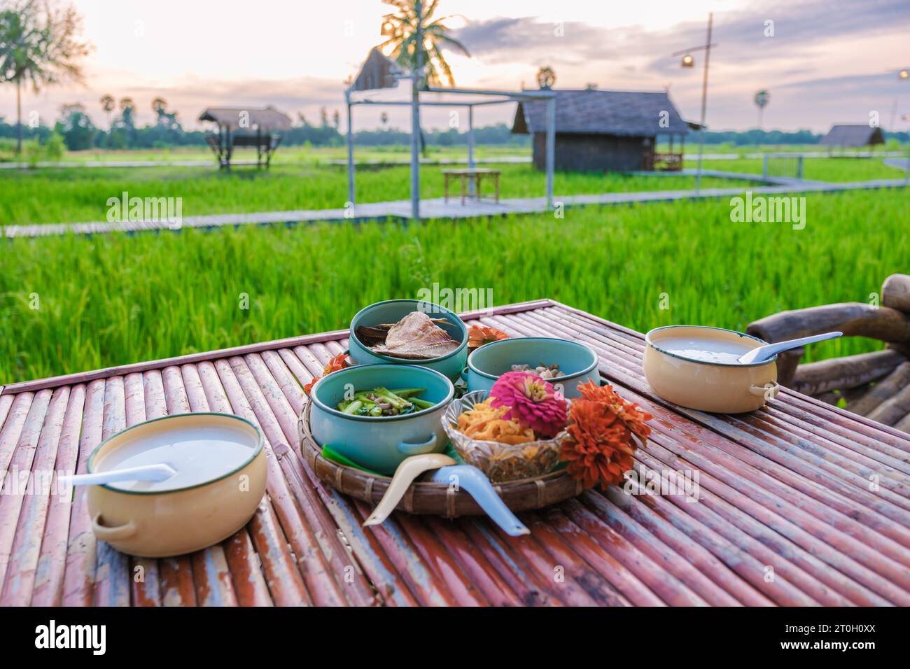 Thai breakfast with a green rice paddy field during sunrise, rice soup ...