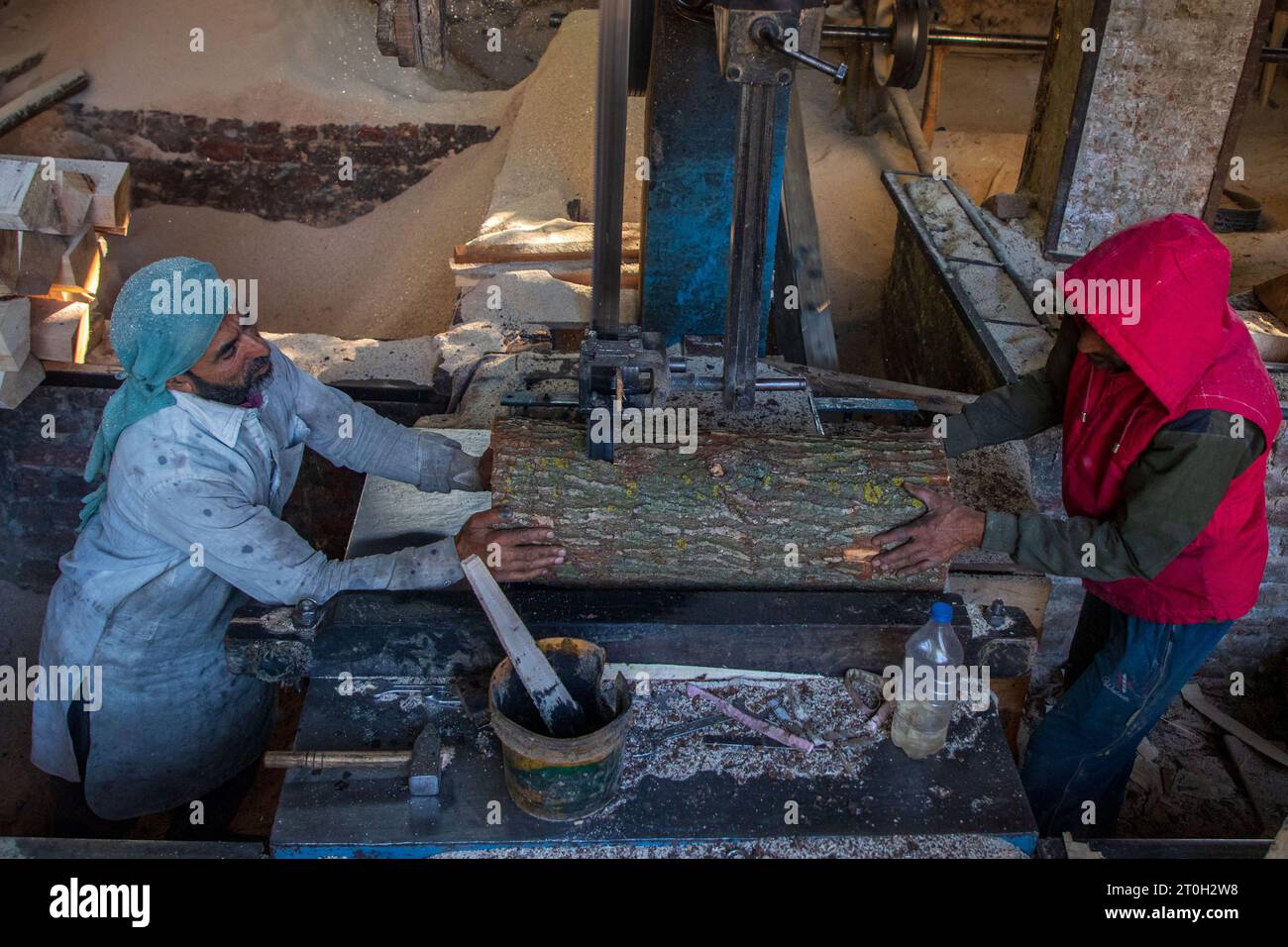 Kashmiri workers cut a willow log with which cricket bats will be made ...