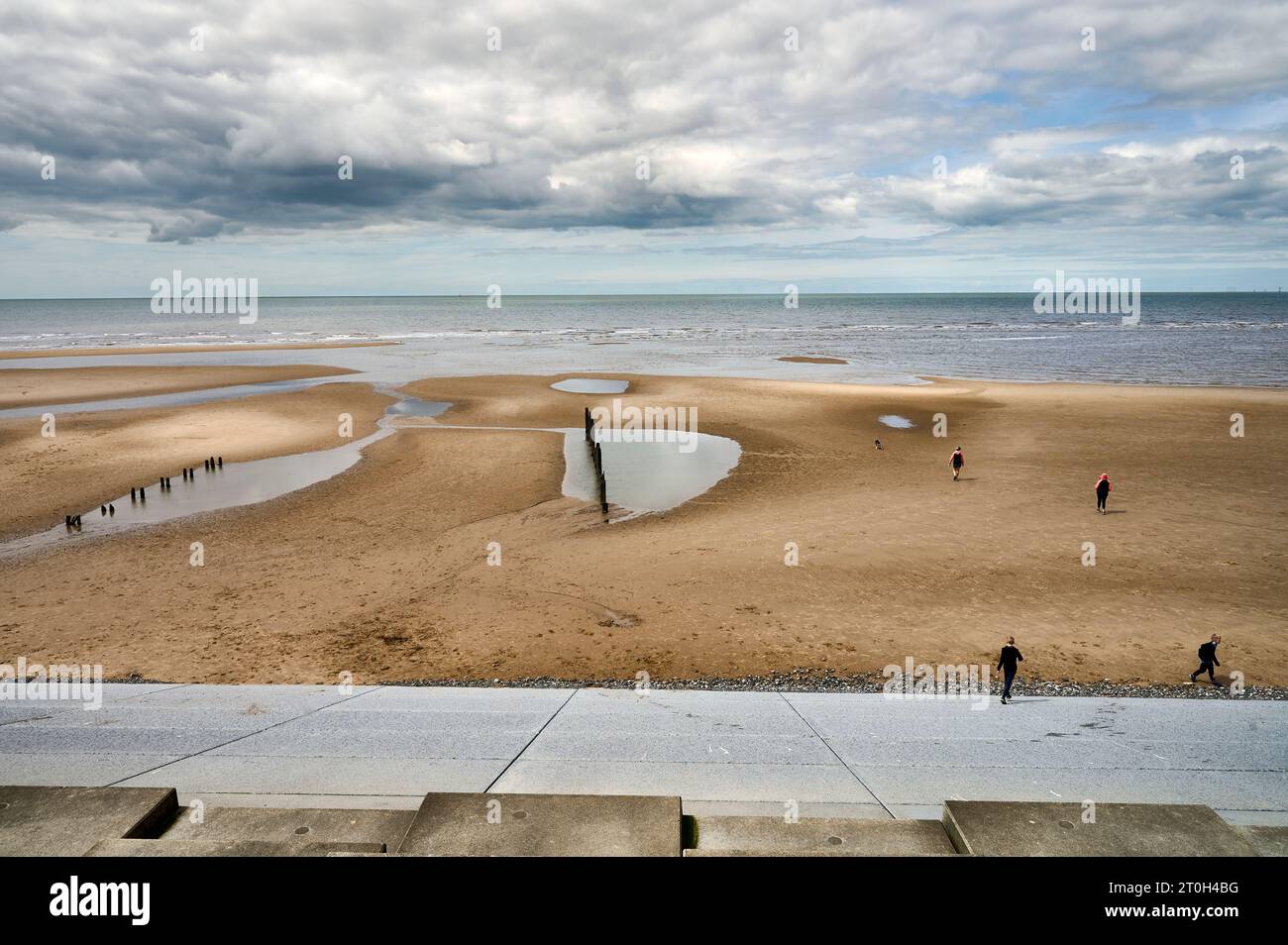 Beach with old broken timber groynes and new seawall Stock Photo - Alamy