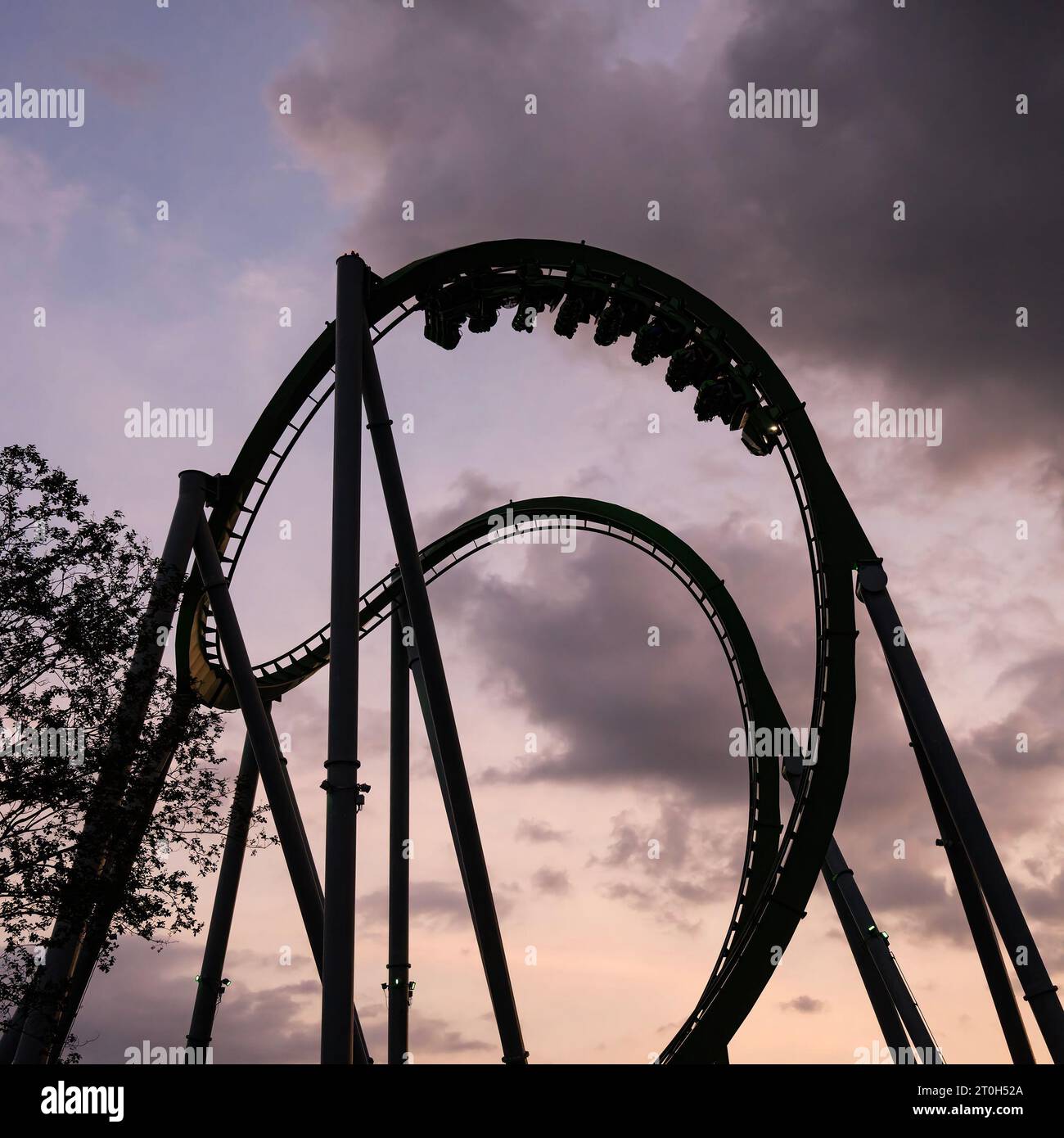 A silhouette of people riding a roller coaster at sunset time on a ...