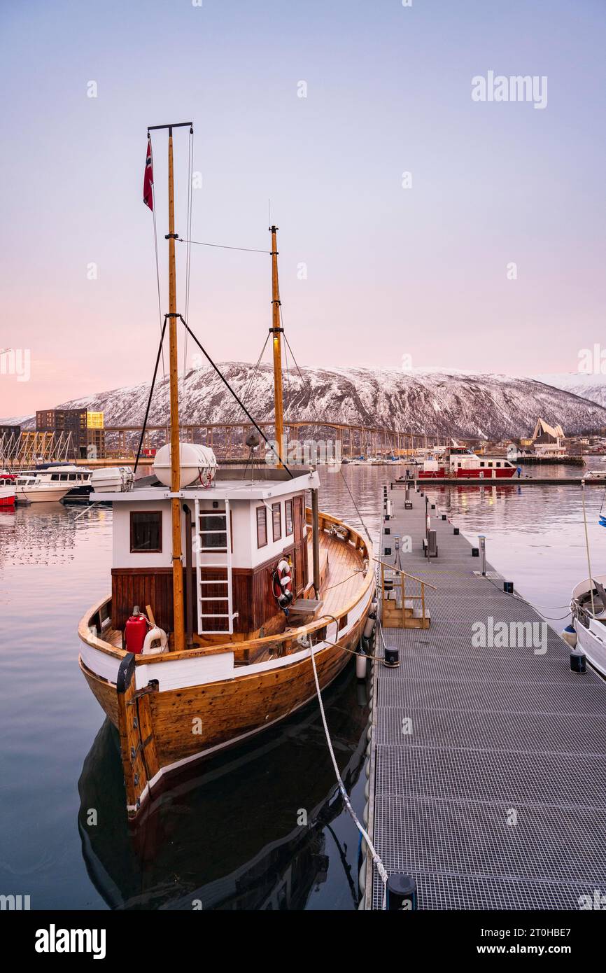 Traditional fishing boat in Tromso harbour, Tromsobrua at the back ...