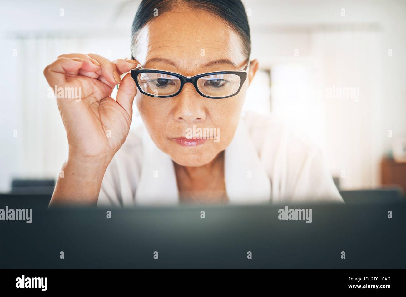Mature woman, glasses and reading on computer for home blog or article ...