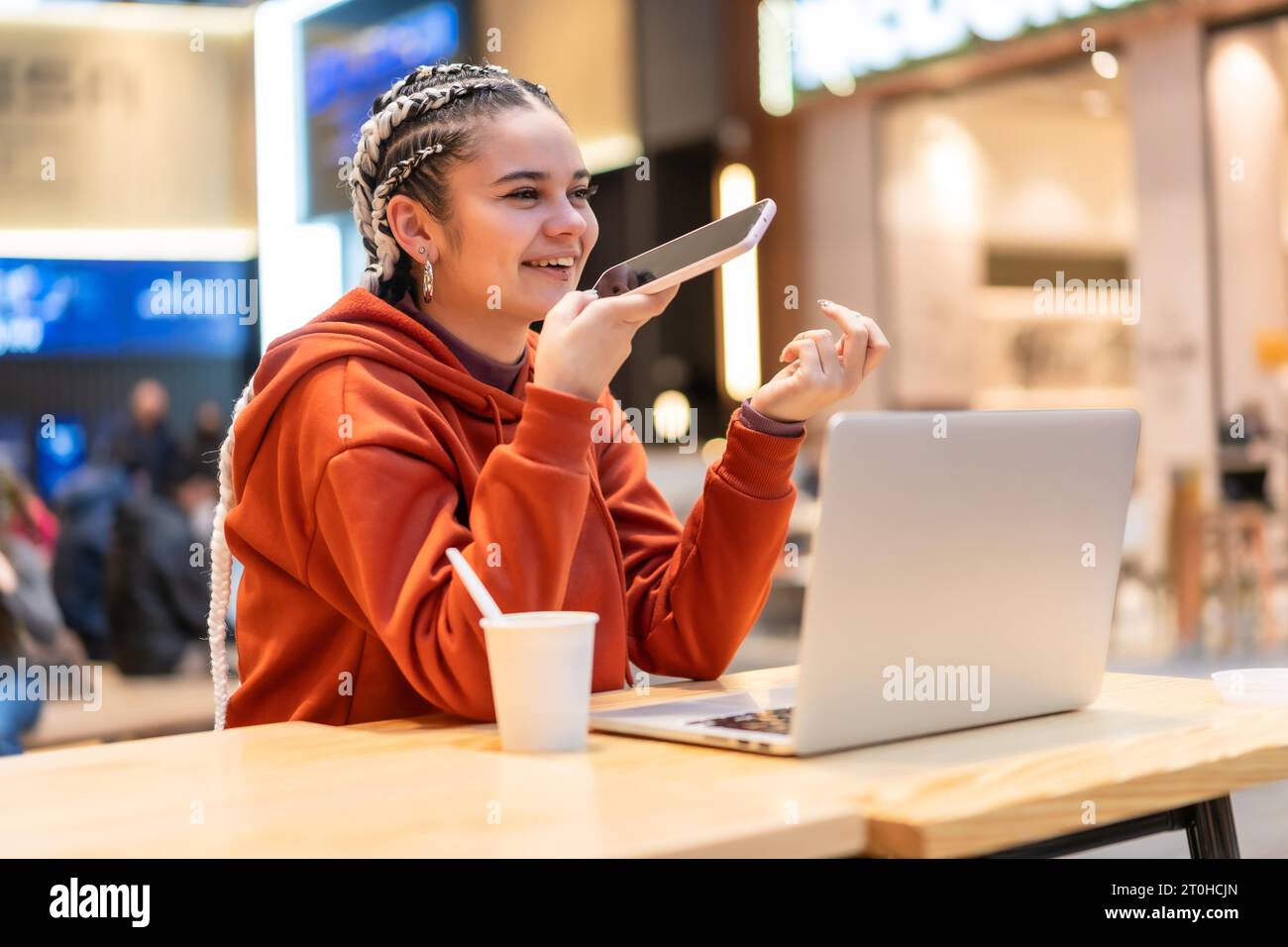 Alternative girl with white braids using a computer in a shopping mall ...