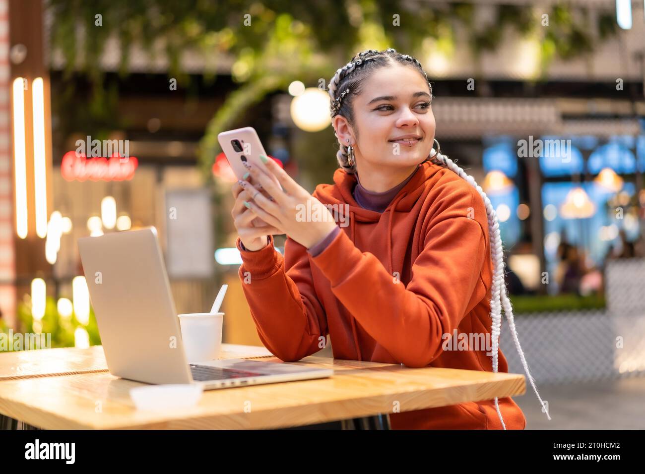 Alternative girl with white braids using a computer in a shopping mall ...