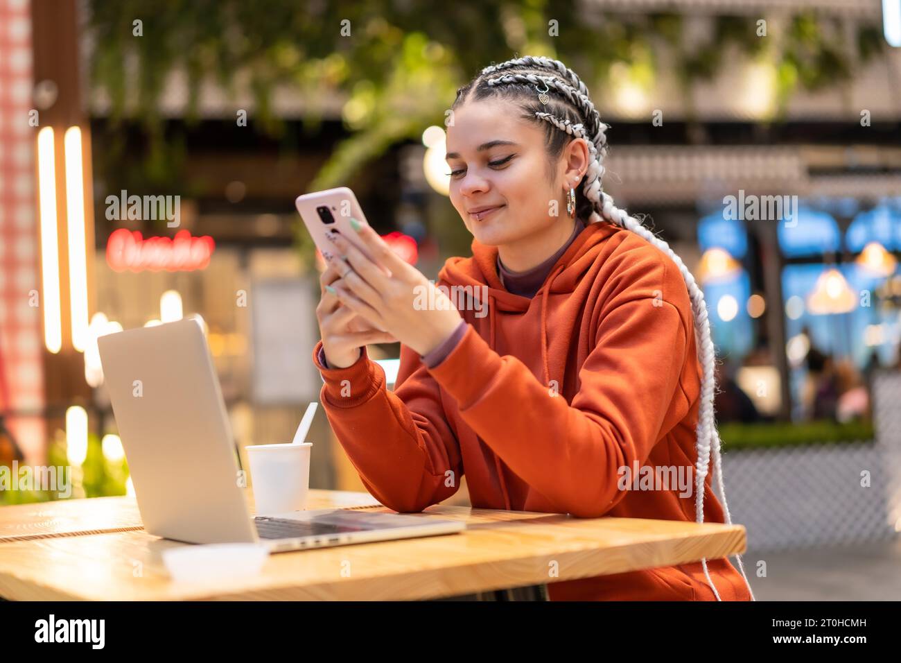Alternative girl with white braids using a computer in a shopping mall ...