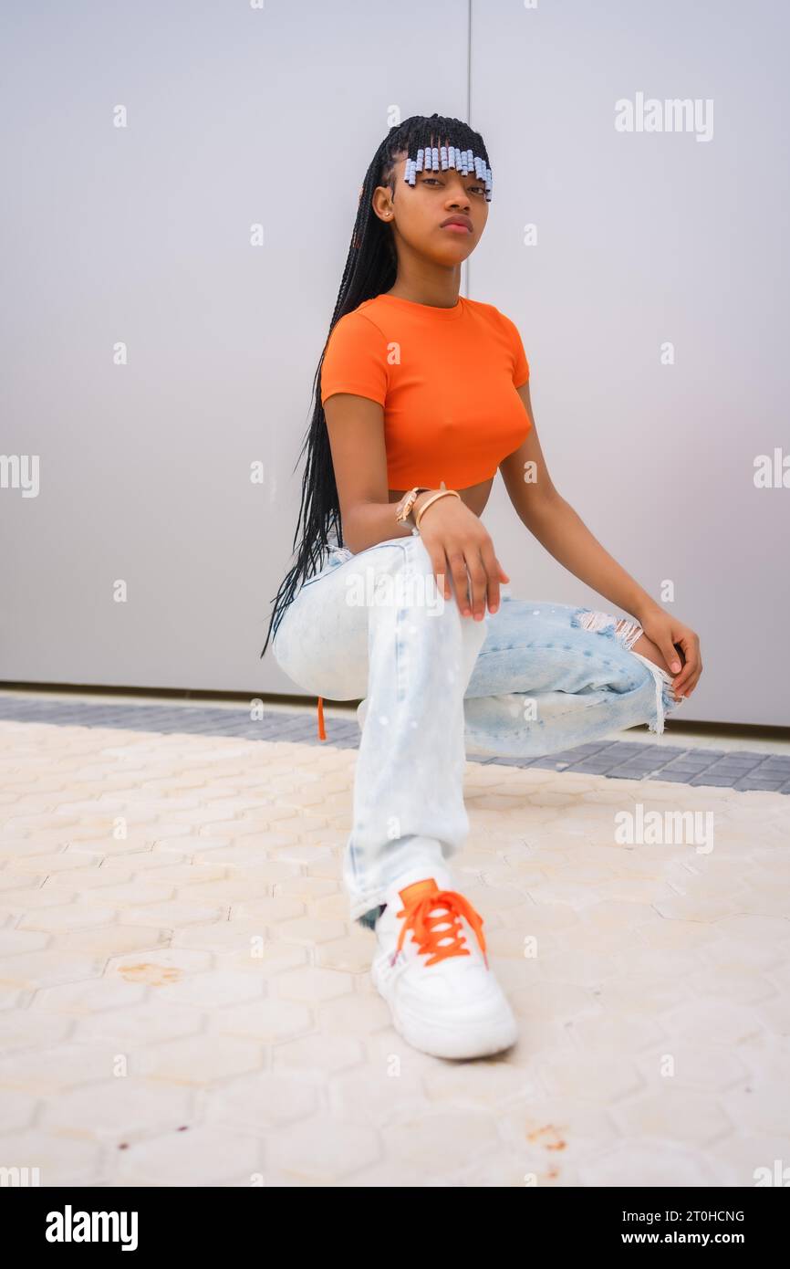 A young trap dancer with braids. Black ethnic girl with orange t-shirt ...