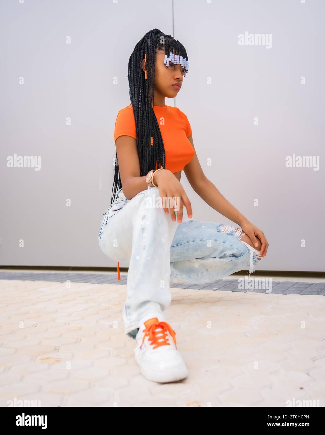 A young trap dancer with braids. Black ethnic girl with orange t-shirt ...