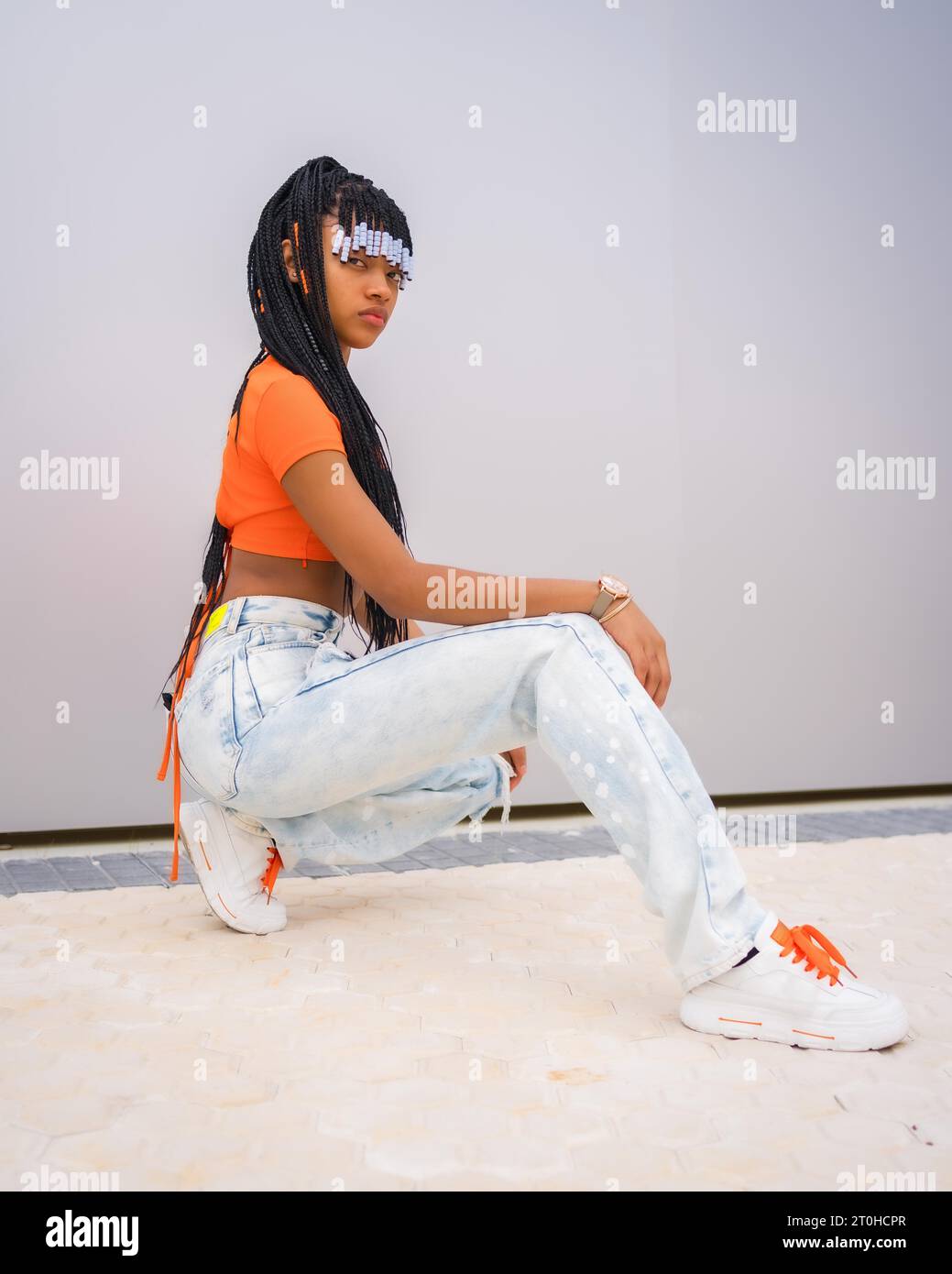 A young trap dancer with braids. Black ethnic girl with orange t-shirt ...