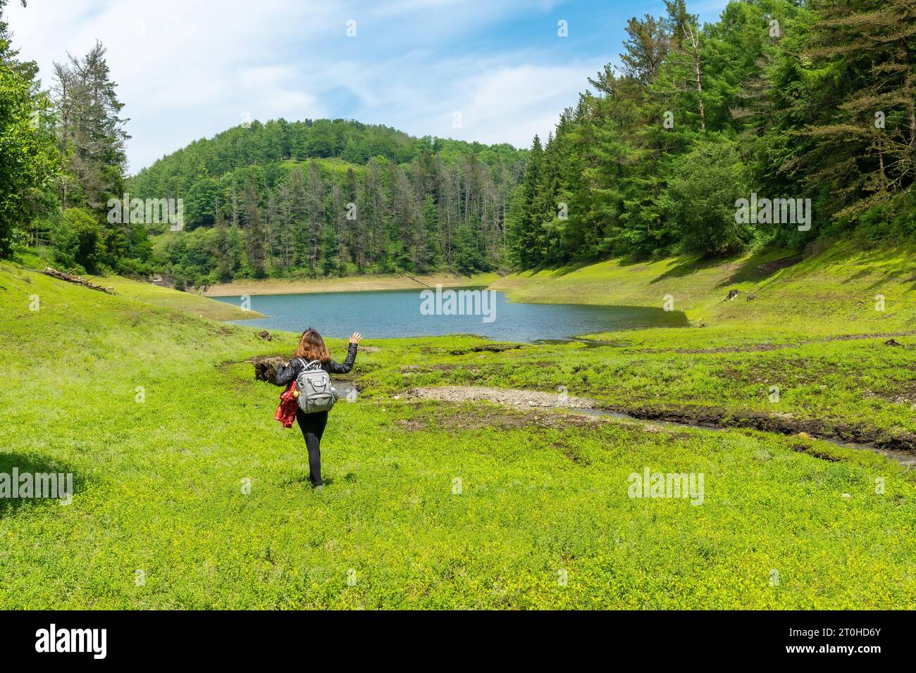 A young woman walking through the Domiko reservoir, a lake with pine ...