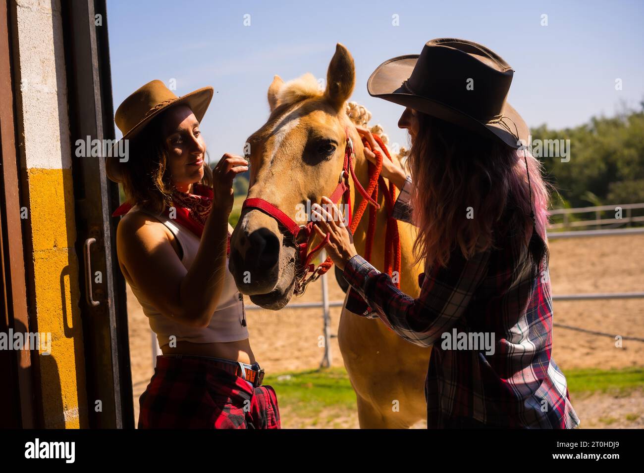 Posed in silhouette of two cowgirl women entering the stable with a ...
