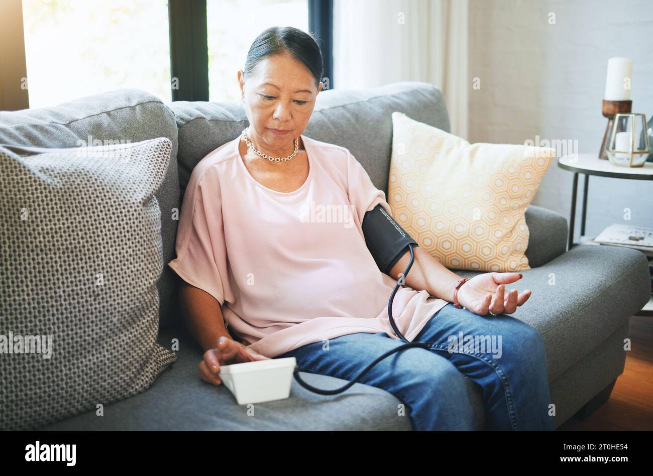 Blood pressure, healthcare and senior woman in living room with ...
