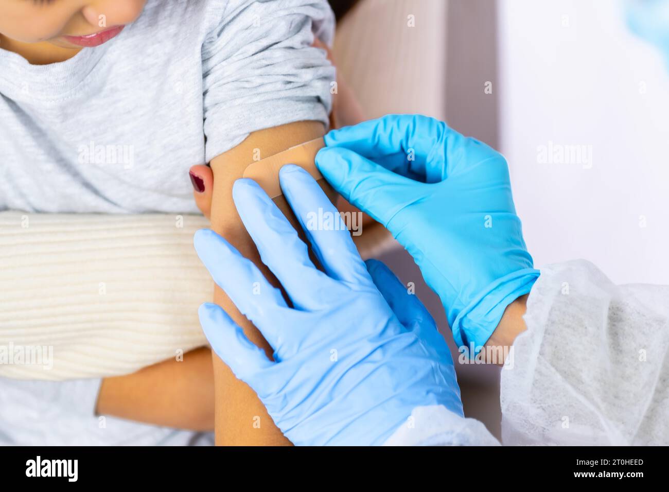 Female doctor applying a plaster to the child after the injection of ...
