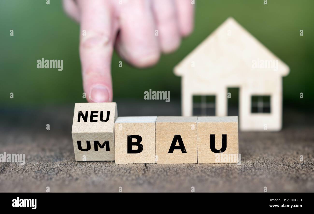 Hand turns wooden cube and changes the German expression 'Umbau ...