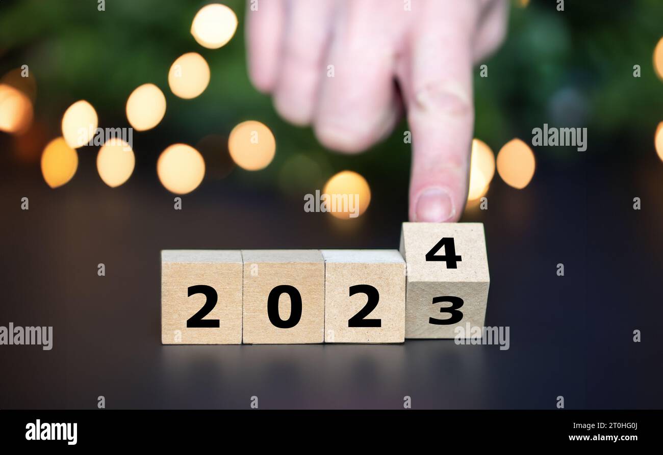 Hand turns cube and changes the year 2023 to year 2024 Stock Photo - Alamy
