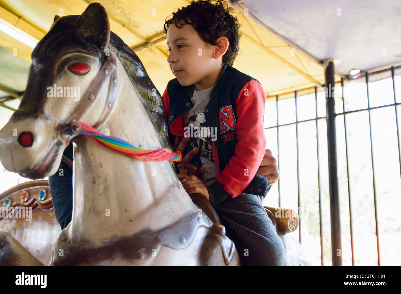 Venezuelan Latino male child, happy riding on pretend horse with his ...