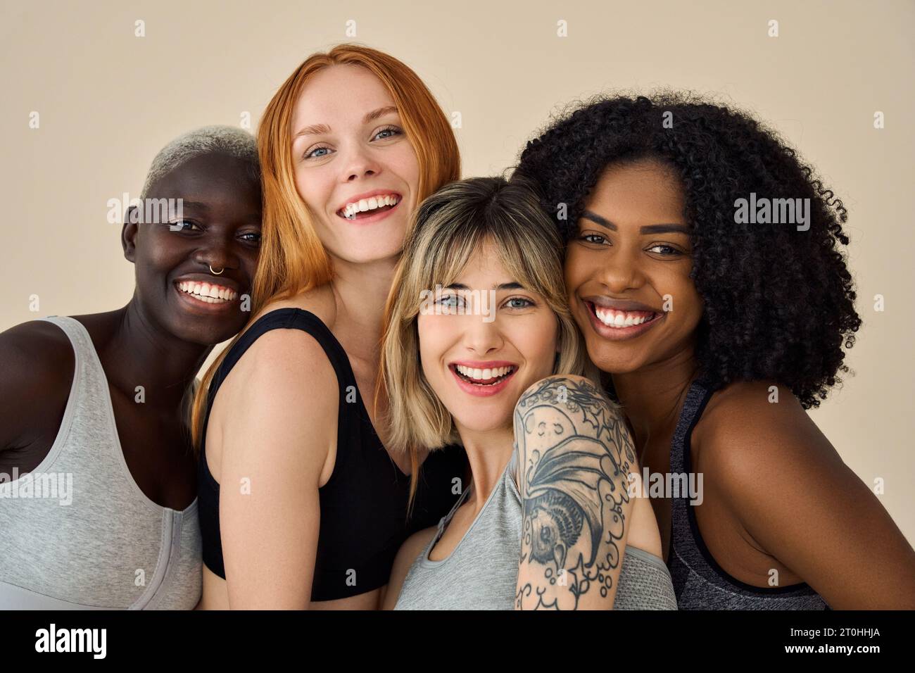 Happy diverse young women models wearing tops on beige background ...