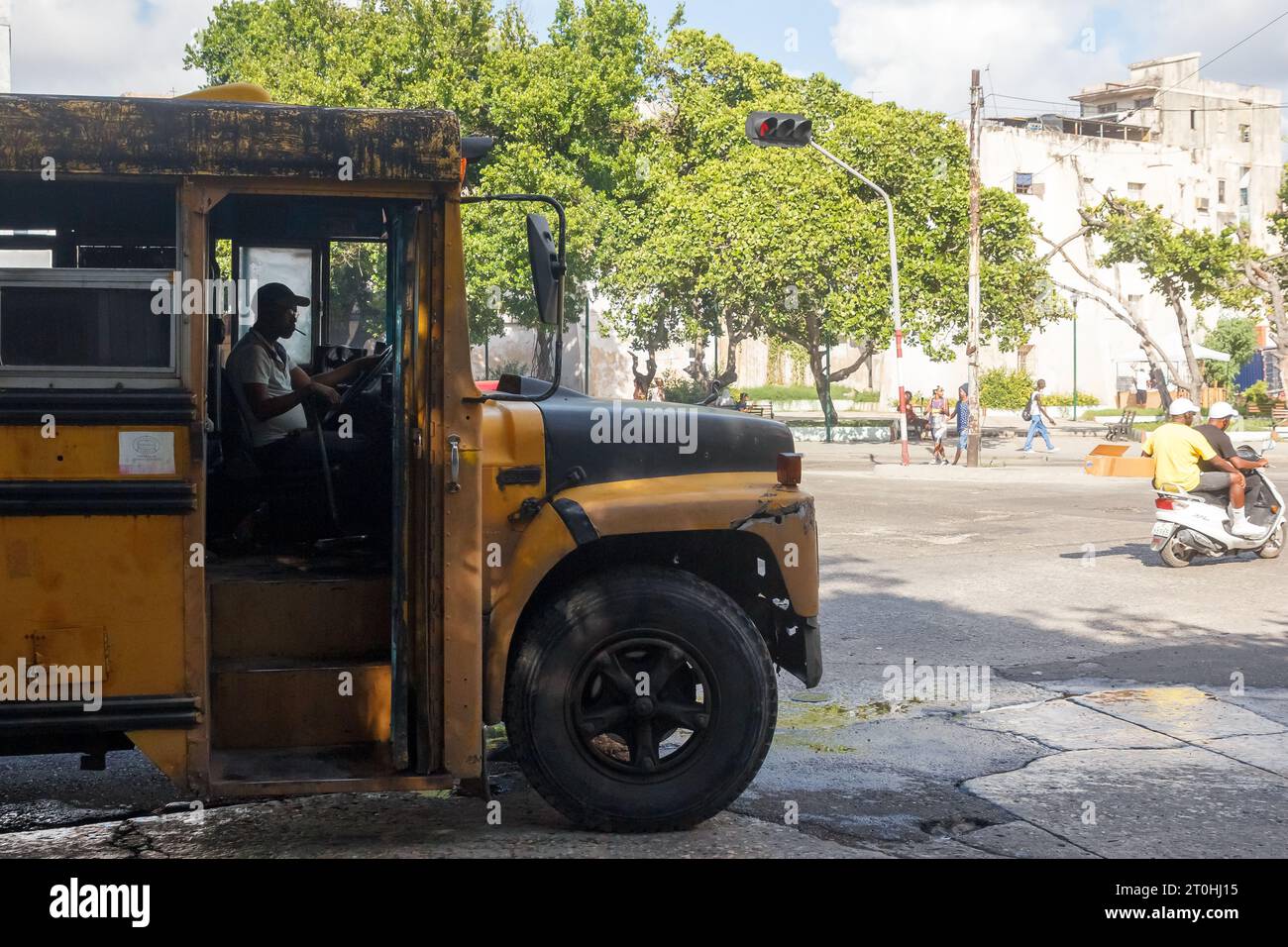 A Cuban man drives an old yellow bus truck in the downtown district ...