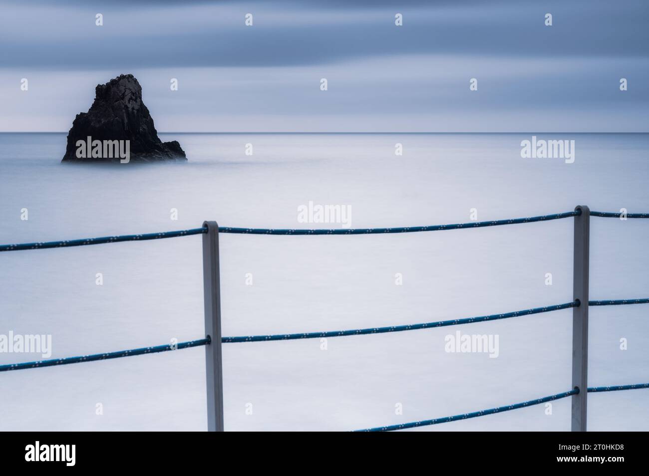 Tranquil blue sea, rock cliff, railing, sky, and scenery at Madeira ...