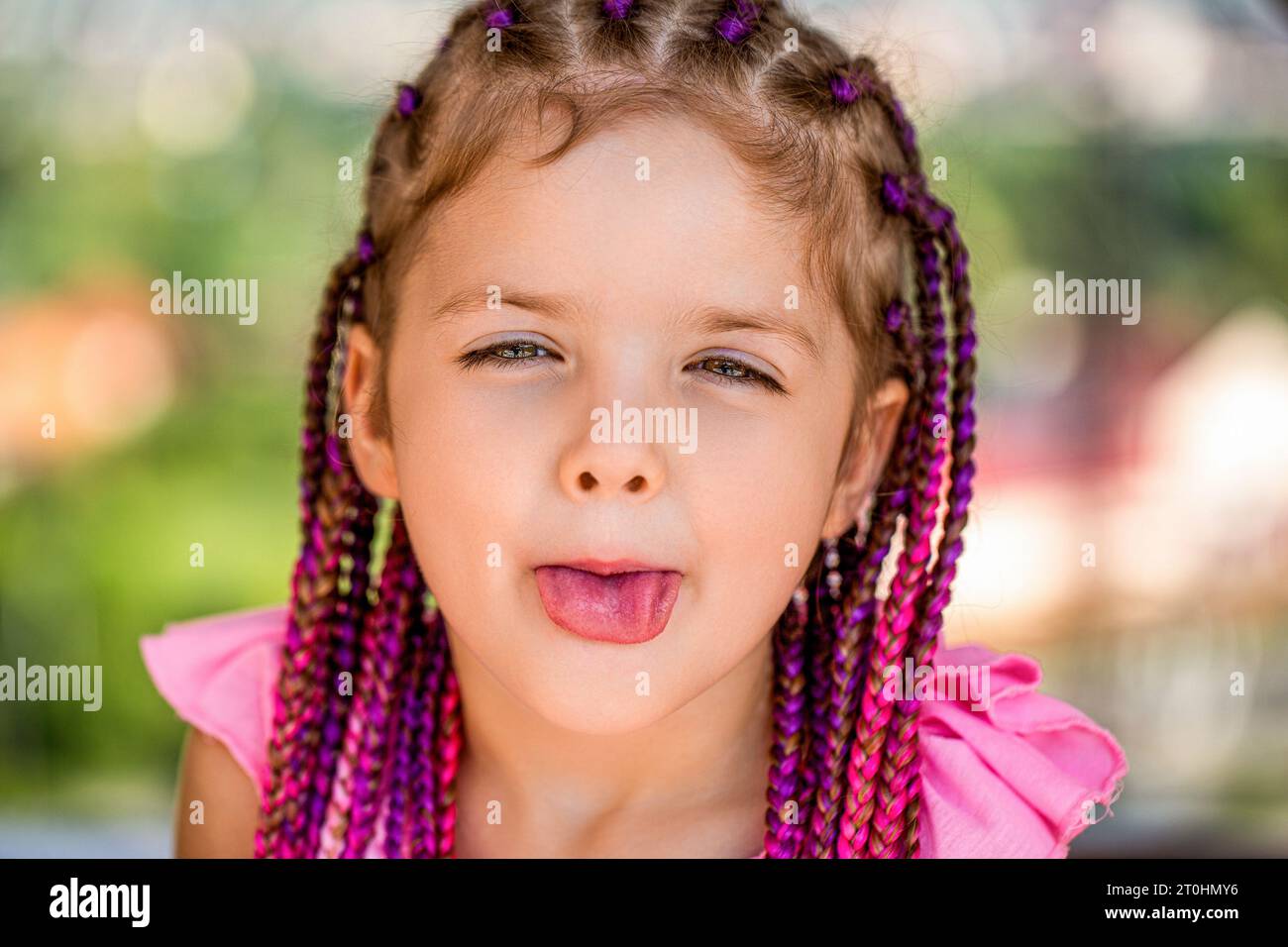 Child sticking out tongue emotional girl. Small girl pink afro-pigtails. Kid girl shows his ...
