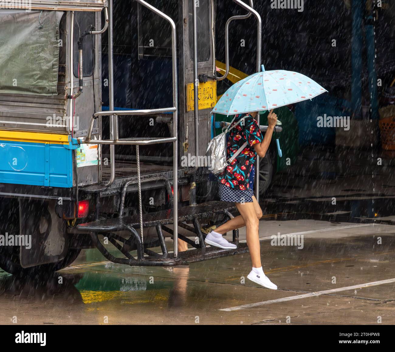 A woman get off the truck - bus on the rainy street, which is a ...