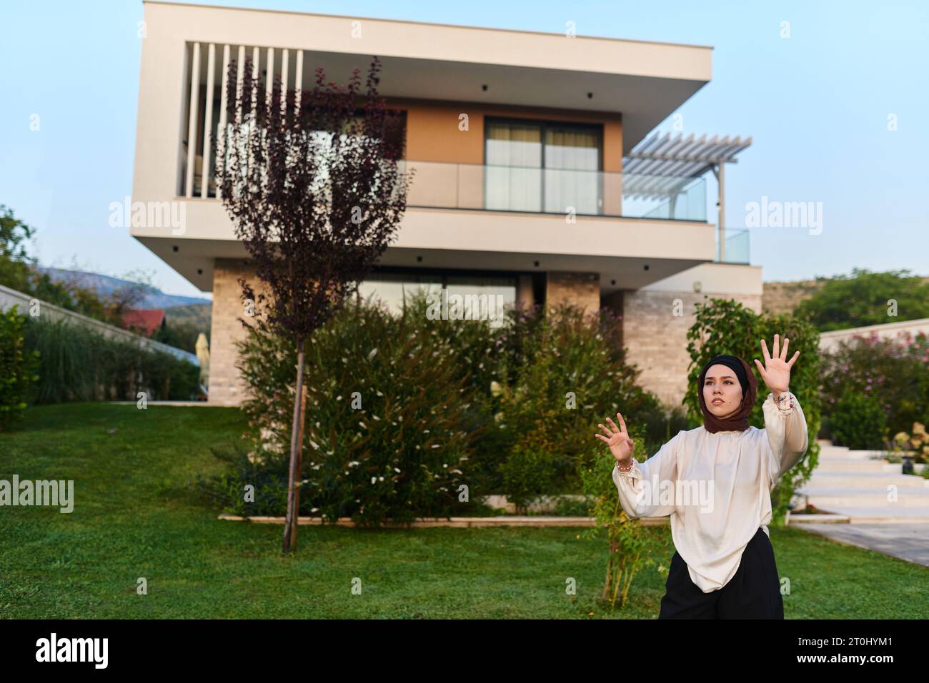 A Modern Hijab Clad Woman Stands In Front Of A Contemporary Villa With 2376