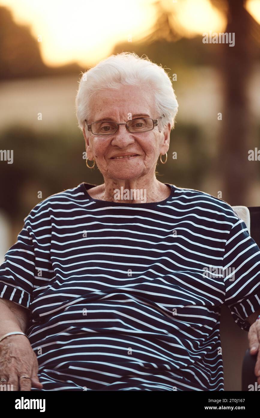 Unfiltered portrait, a real elderly woman sits gracefully in a chair ...
