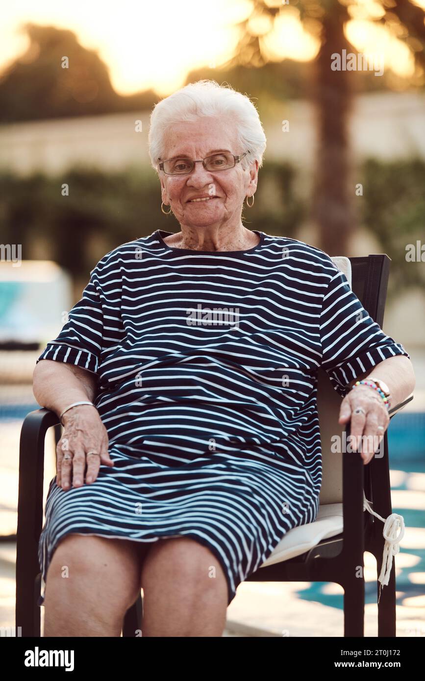Unfiltered portrait, a real elderly woman sits gracefully in a chair ...
