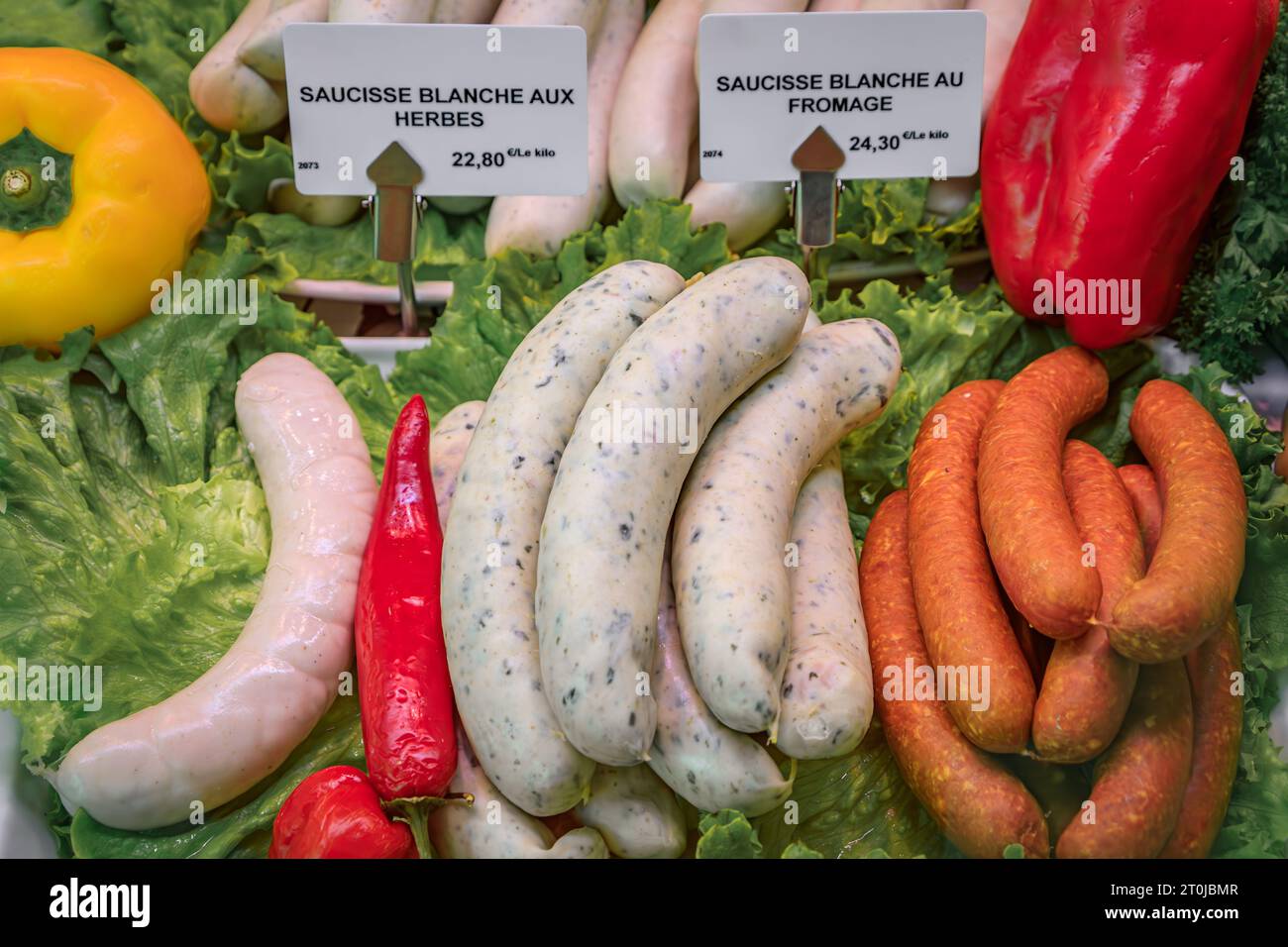 Artisanal white sausages with cheese and herbs on display at a butcher ...