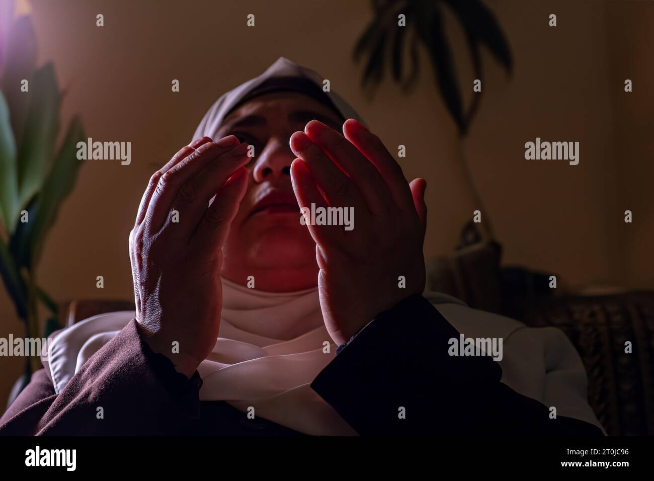 A Muslim woman raises her prayers to God to remove the affliction and ...