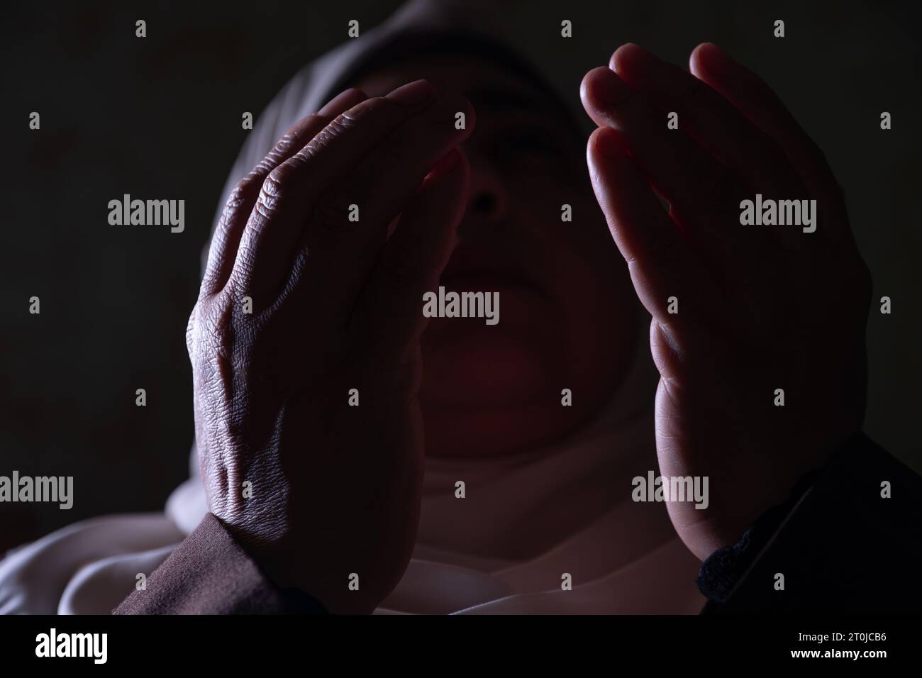 A Muslim woman raises her prayers to God to remove the affliction and ...