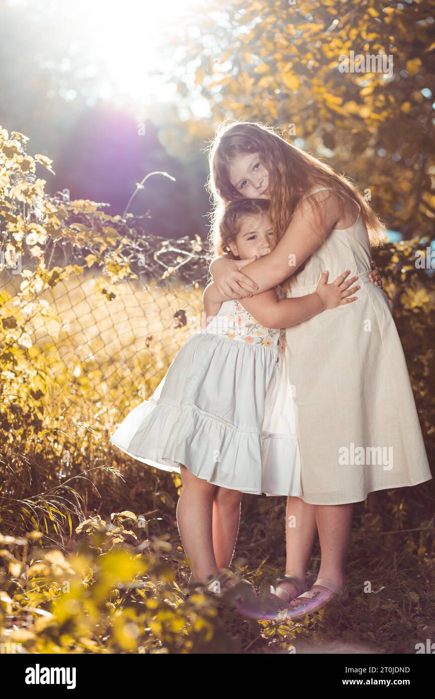 Two little girls, sisters in white dresses hugging Stock Photo - Alamy