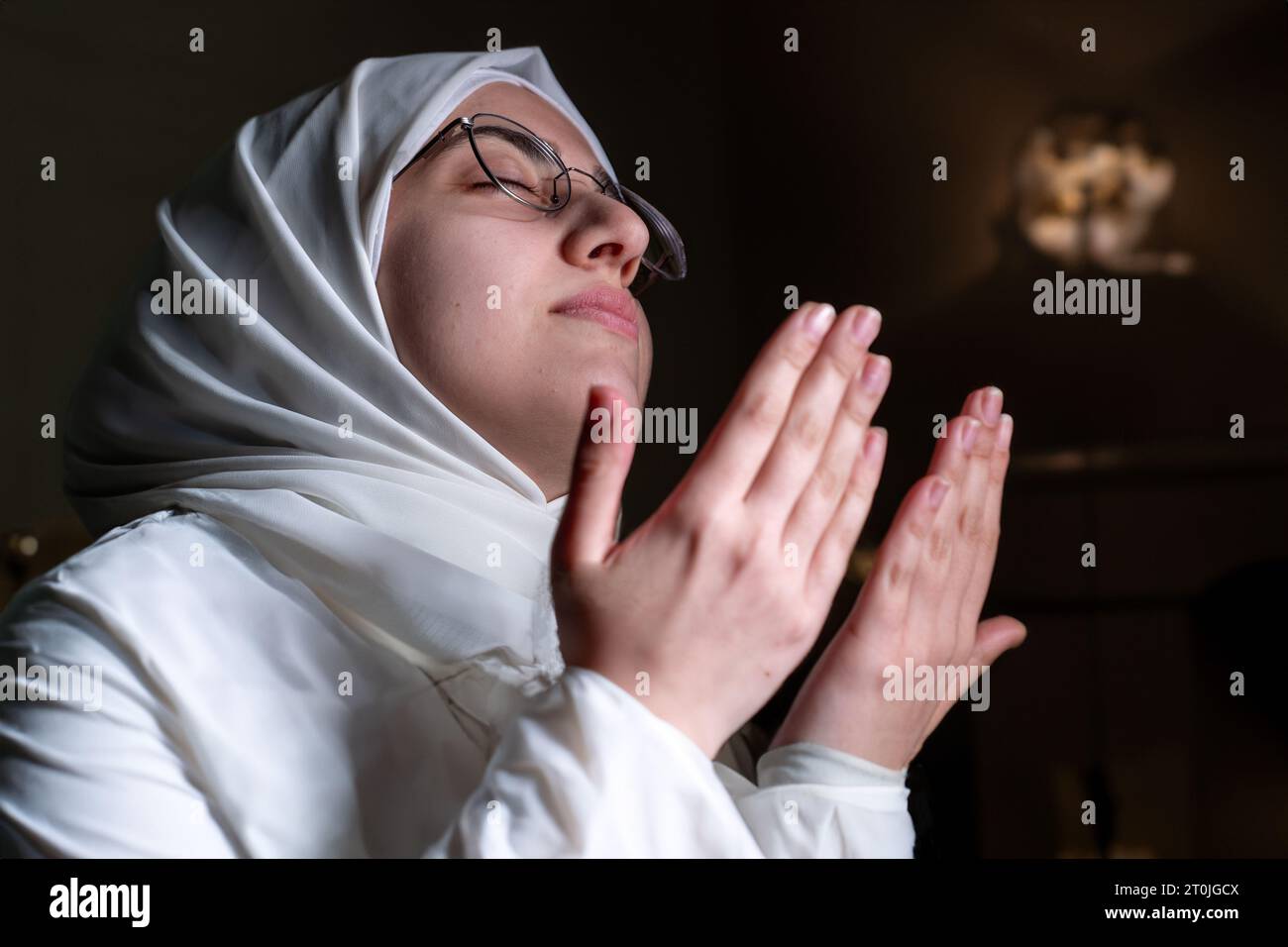 A Muslim woman raises her prayers to God to remove the affliction and ...