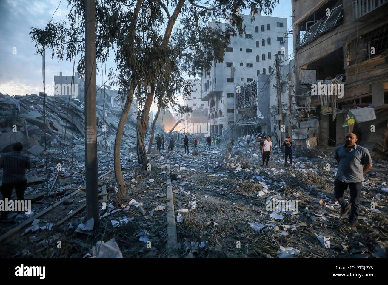 People walk atop the rubble of a tower destroyed in an Israeli air ...