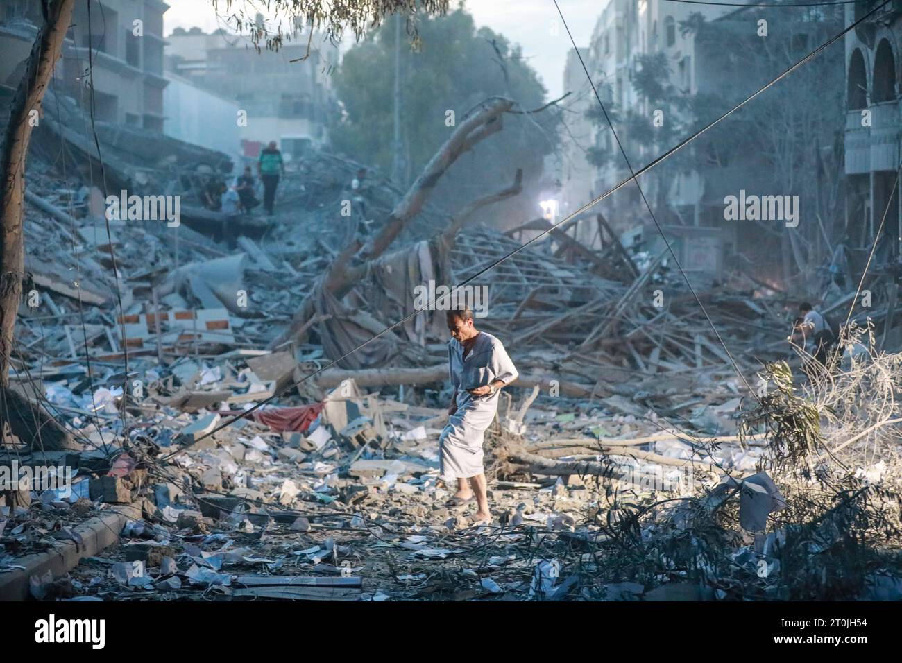 People walk atop the rubble of a tower destroyed in an Israeli air ...