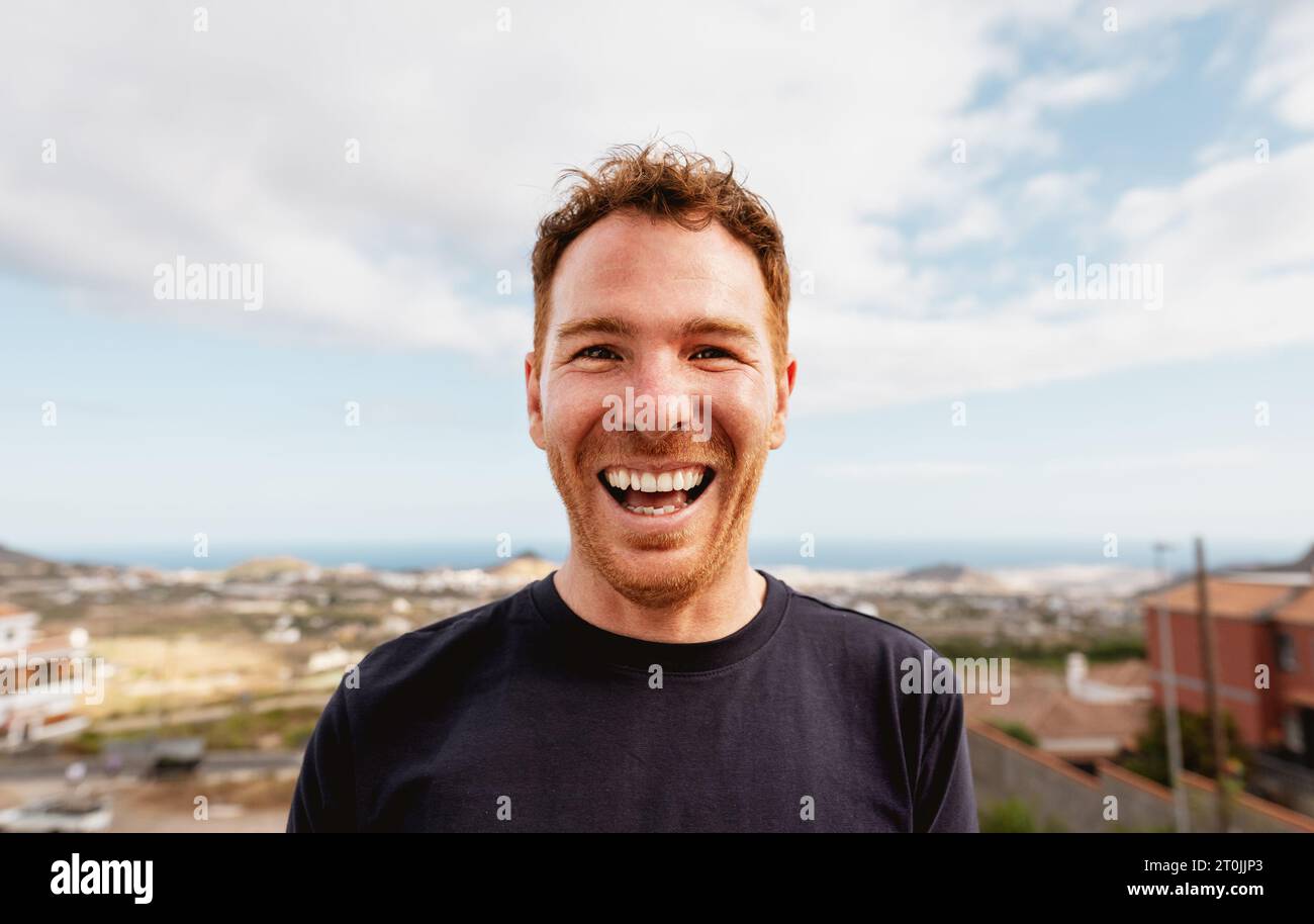 Happy Caucasian young man smiling in front of camera at house rooftop ...