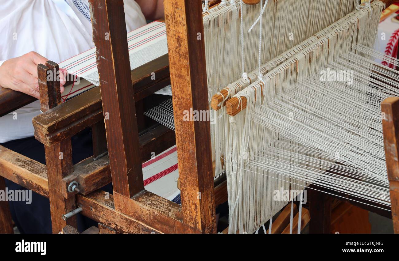 ancient wooden loom for weaving fabrics with many white threads that ...