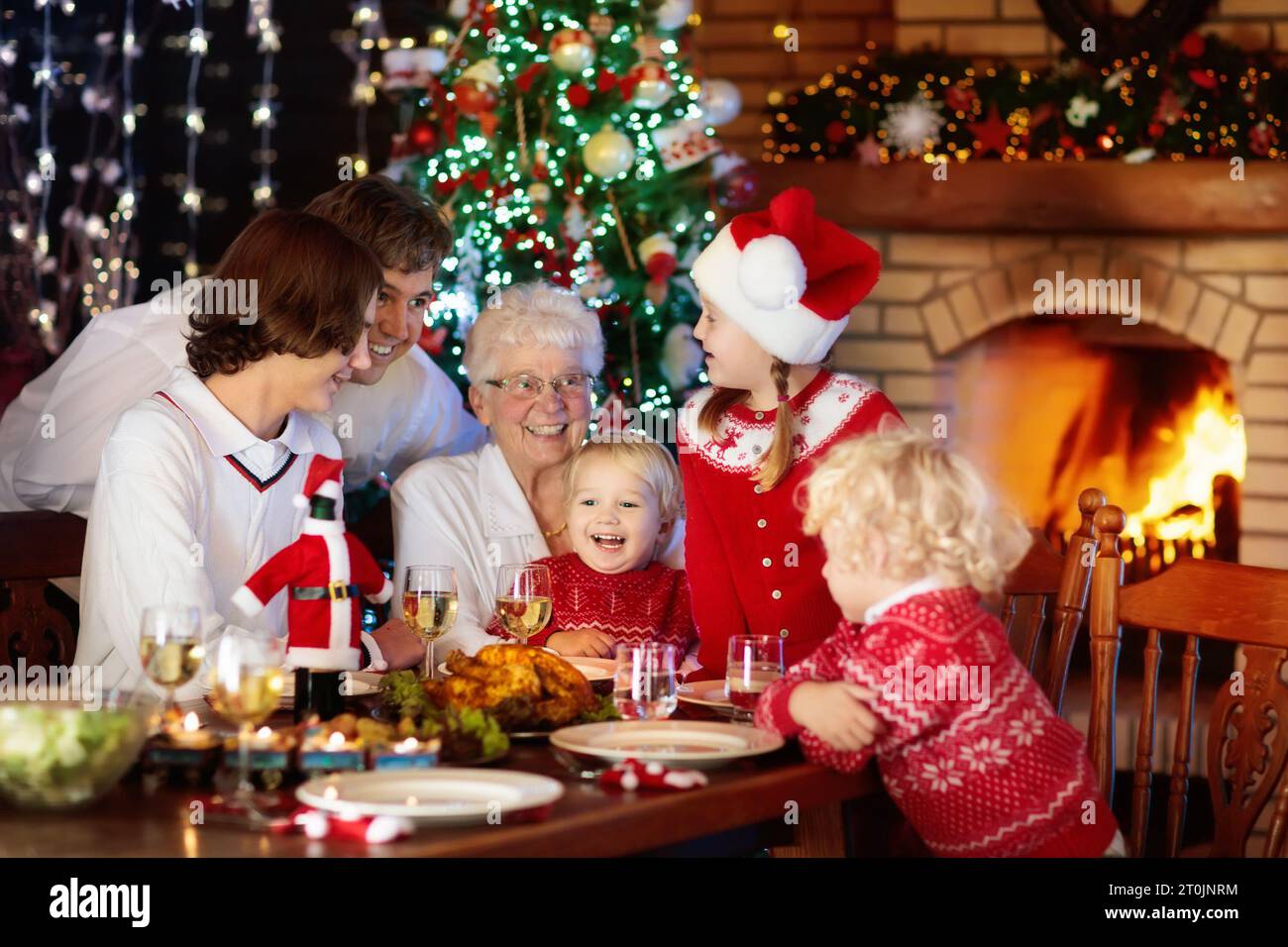 Family with children eating Christmas dinner at fireplace and decorated ...