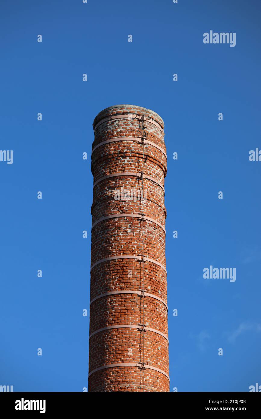 high chimney made with exposed bricks of a buttock factory and the blue ...