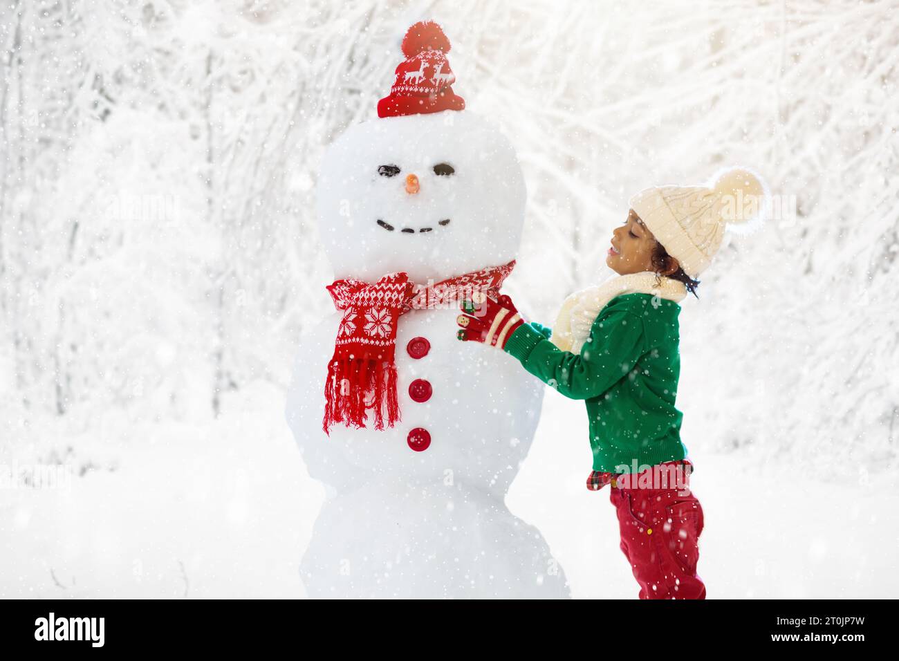 Child building snowman. Kids build snow man. Boy playing outdoors on ...