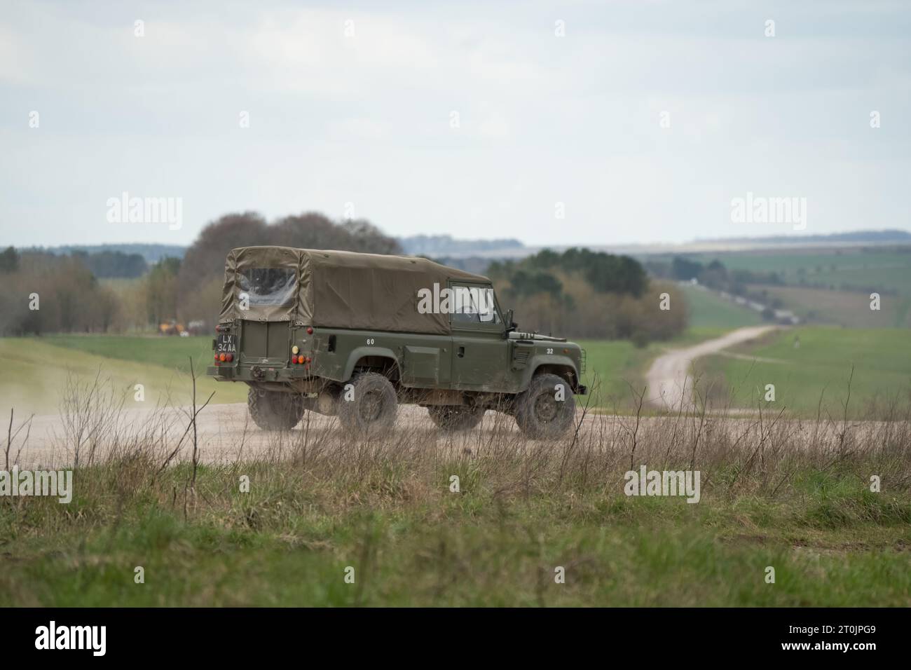 British army Land Rover Defender Wolf driving along a dusty chalk track ...