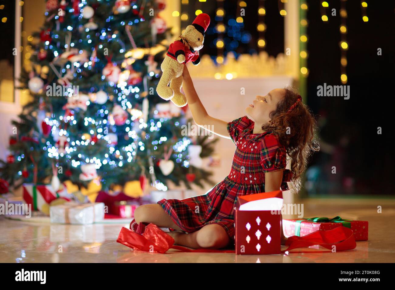 Child opening present at Christmas tree at home. Kid in Santa pajamas ...