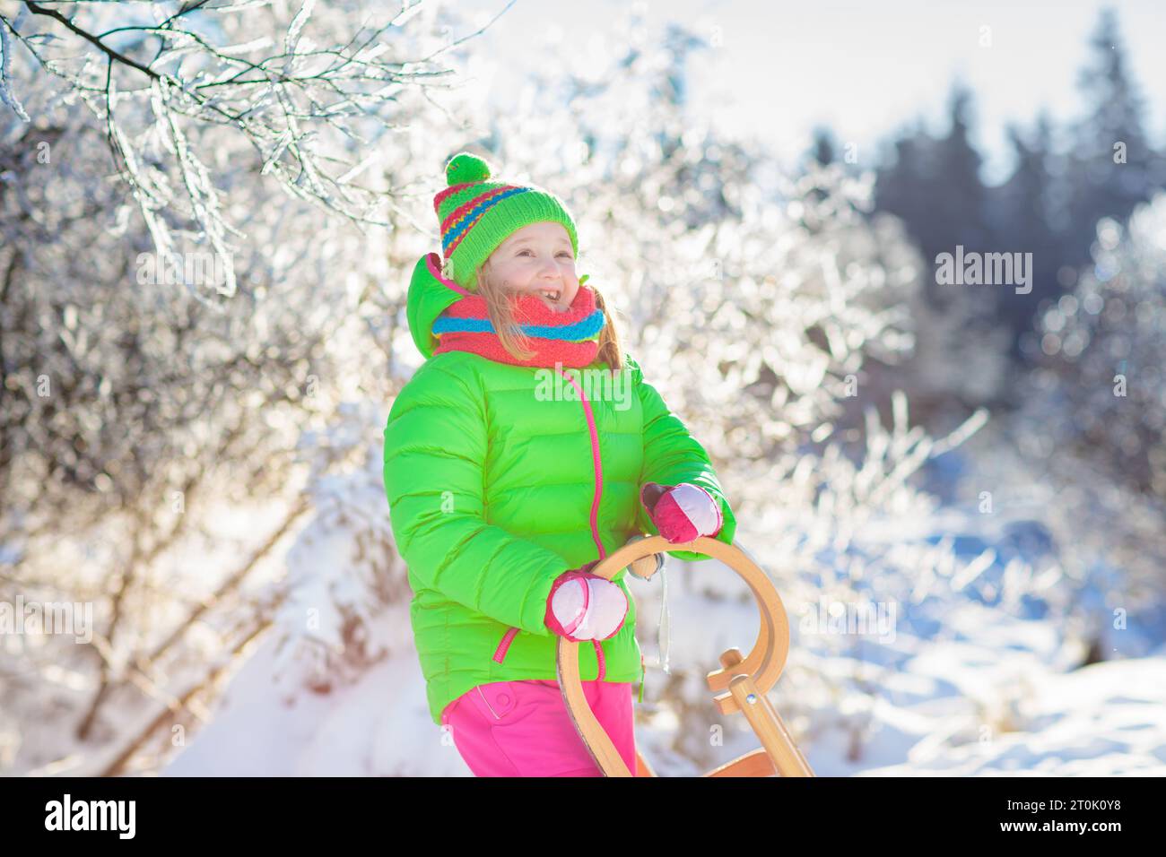 Little girl enjoying a sleigh ride. Child sledding. Toddler kid riding a sledge. Children play ...