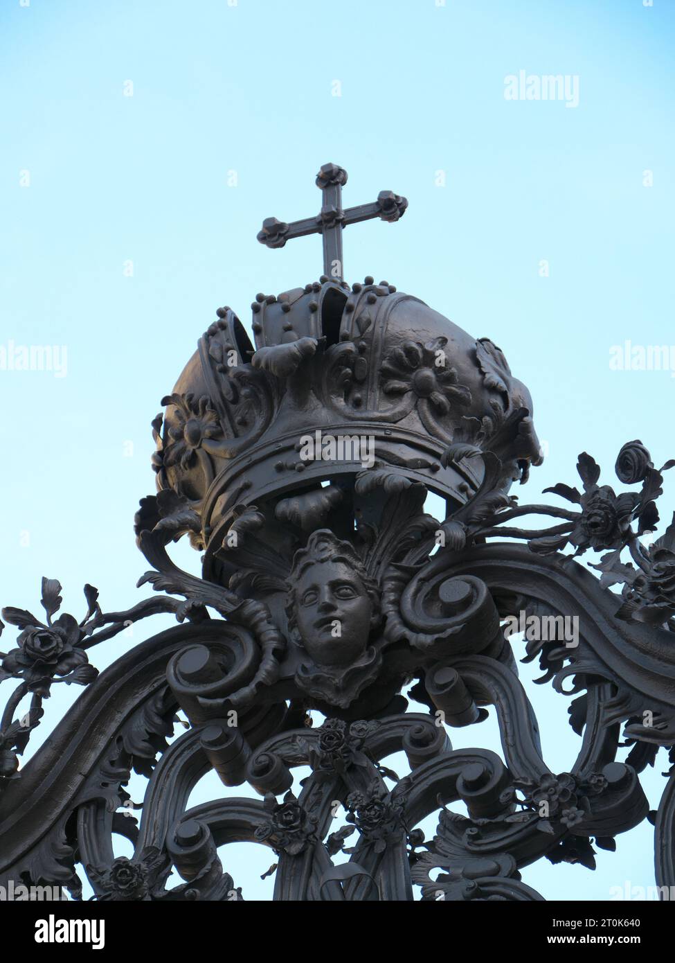 Wrought iron crown, cross and face on a gateway to the courtyard garden ...