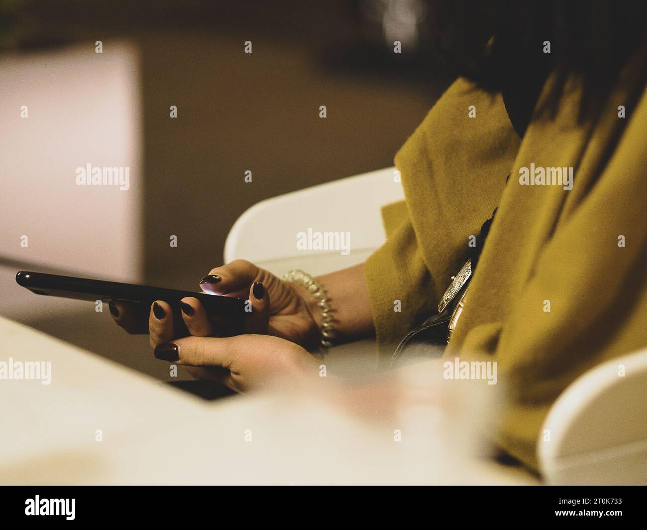 A female adult sitting in a chair with a mobile phone held up to her ...