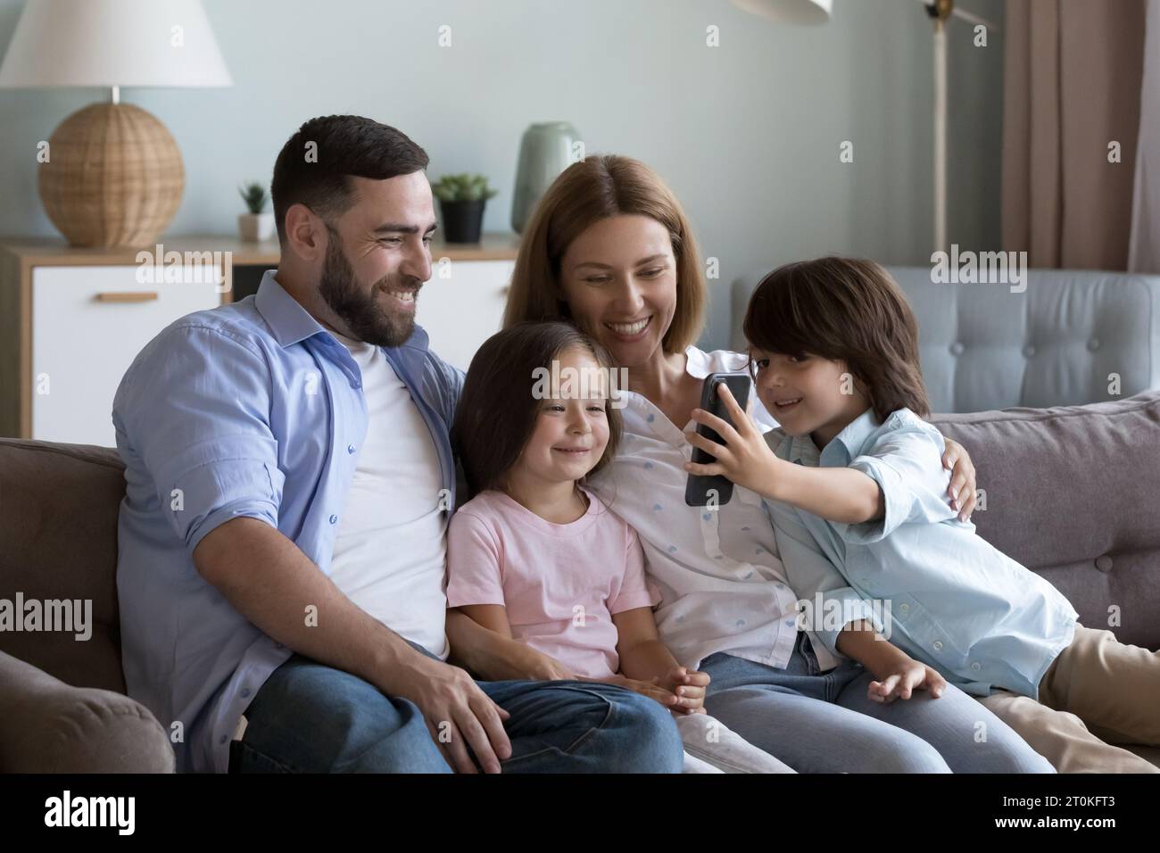 Joyful gen Z boy showing mobile phone screen to parents Stock Photo - Alamy
