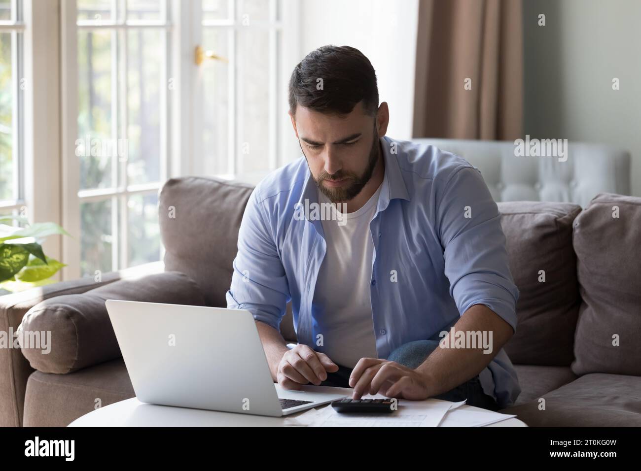 Serious millennial laptop user man counting budget Stock Photo - Alamy