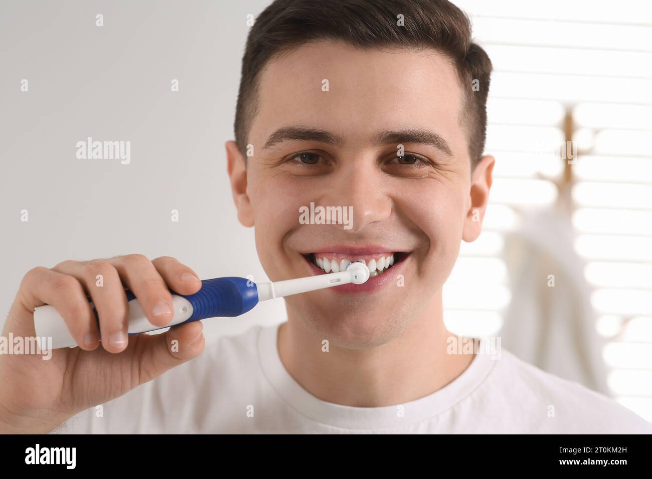 Man brushing his teeth with electric toothbrush indoors Stock Photo - Alamy